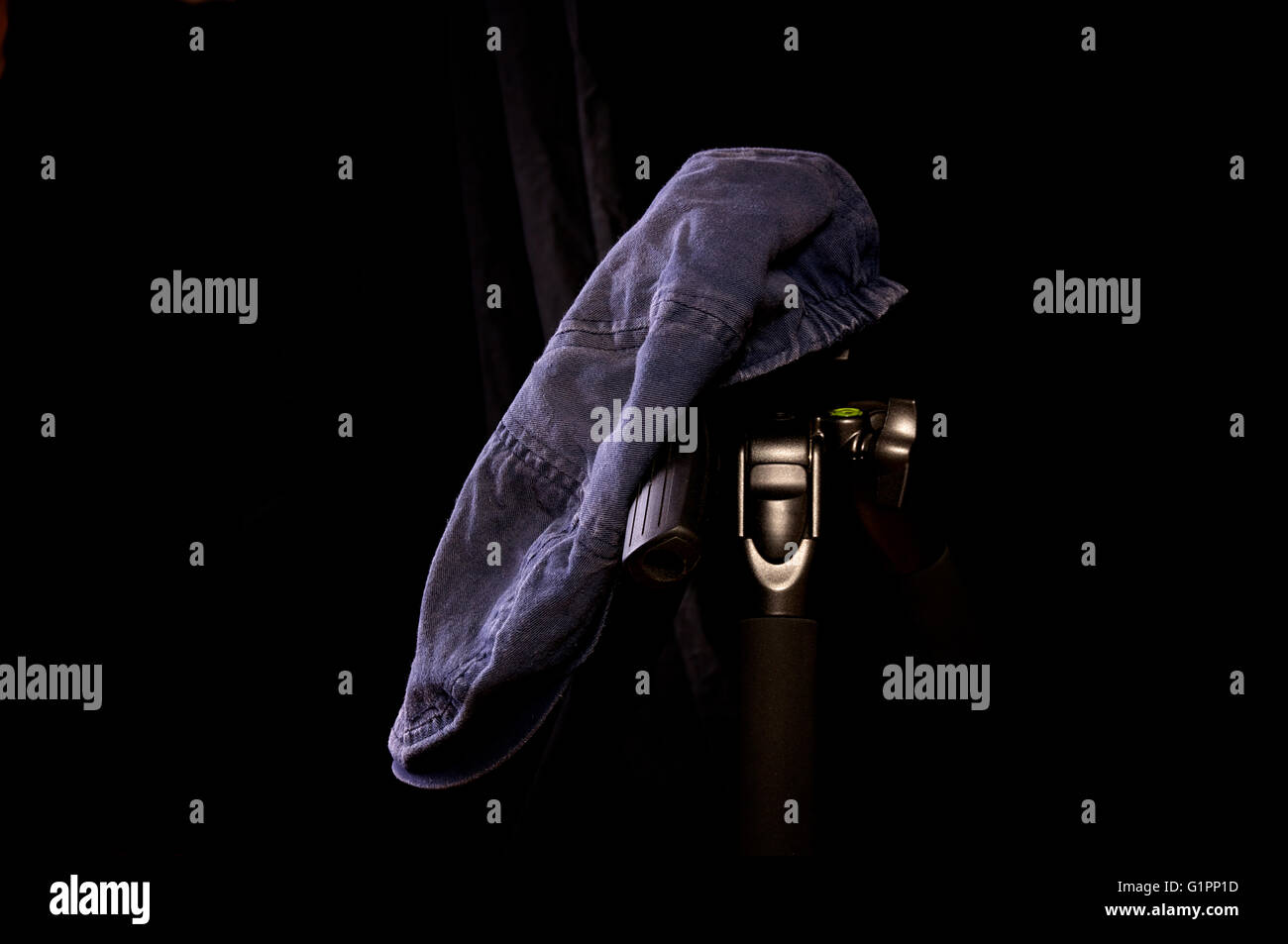 An old worn blue driver's cap against a black background. Hat is on ...