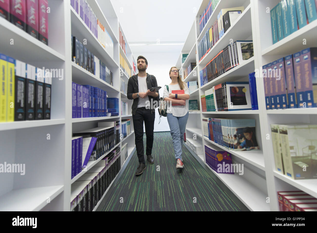 happy students group in school library selecting books to read and ...