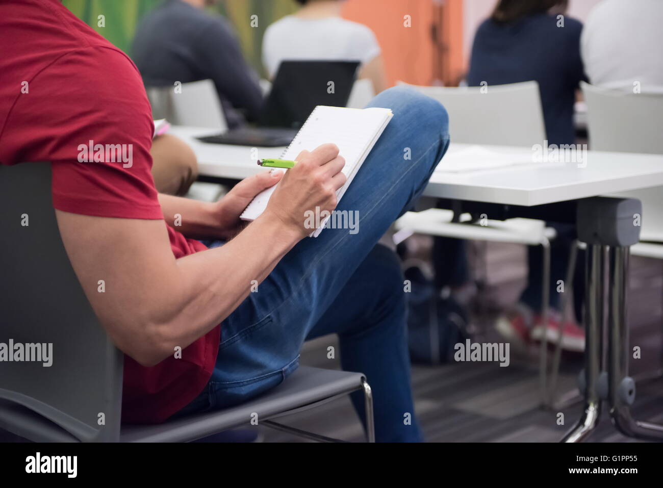 male student taking notes in classroom. business education concept ...