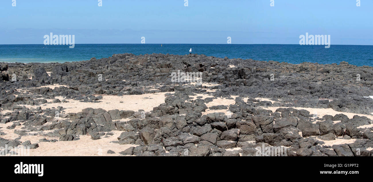 Scenic view of the calm Indian Ocean with ancient grey weathered basalt ...