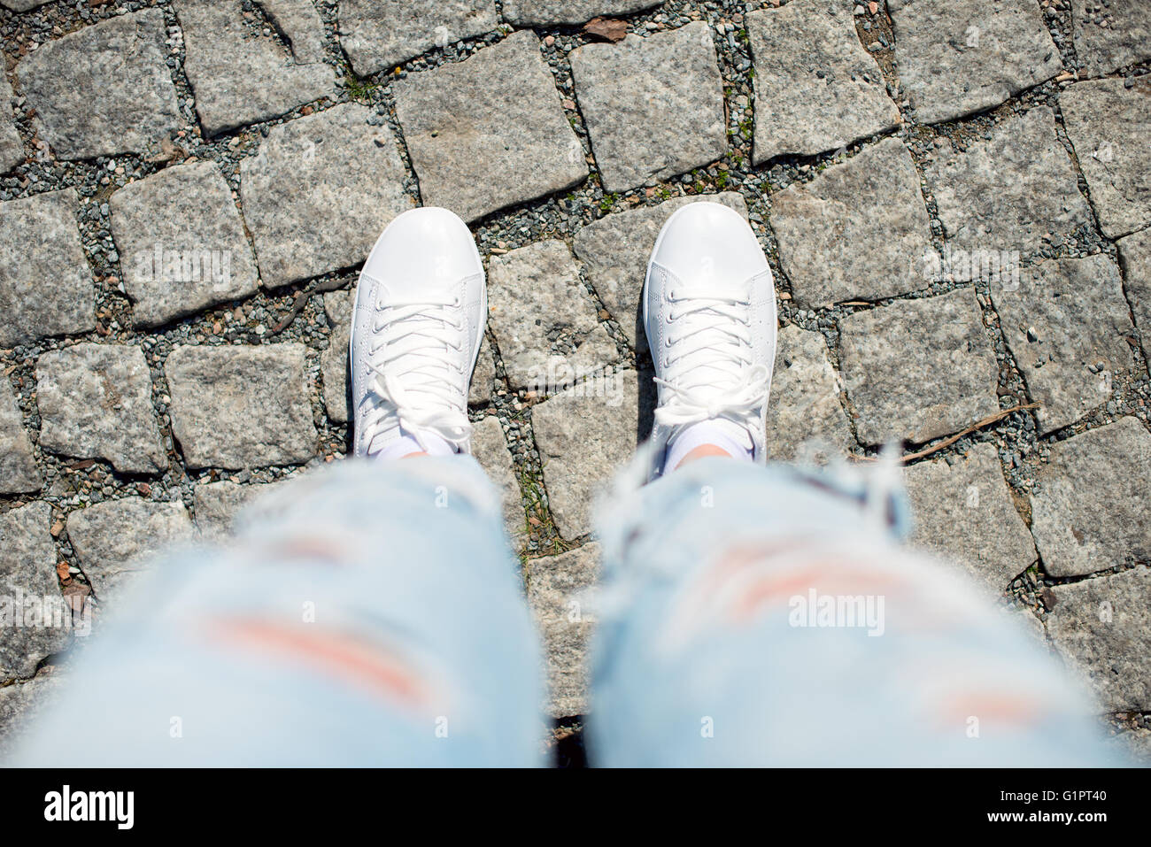 Legs in female sneakers on the pavement. Top view Stock Photo - Alamy