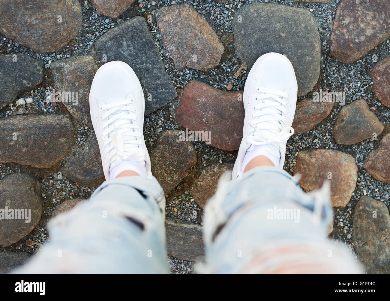 Legs in female sneakers on the pavement. Top view Stock Photo - Alamy
