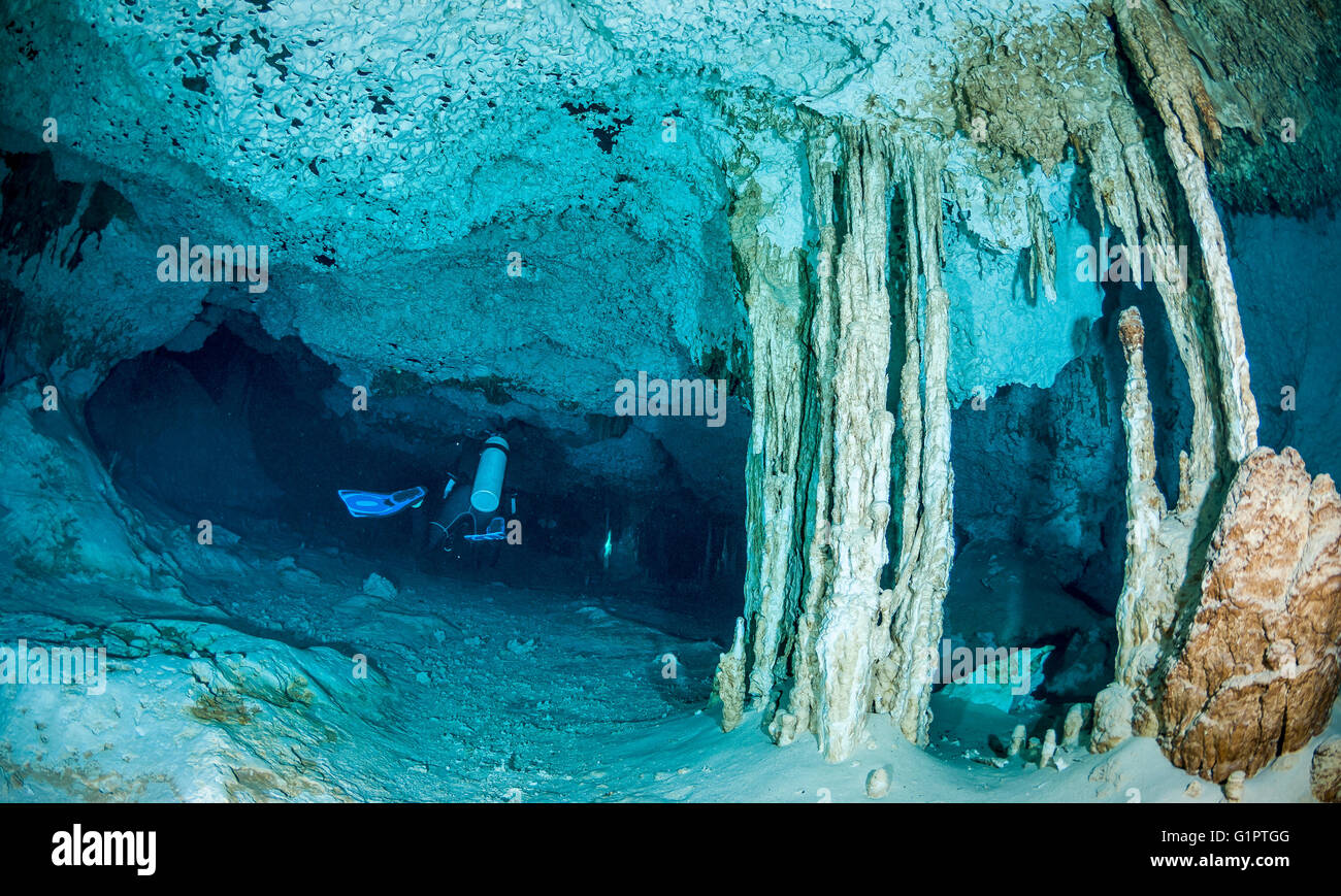 Scuba diver swimming through limestone formations of a Mexican cenote ...