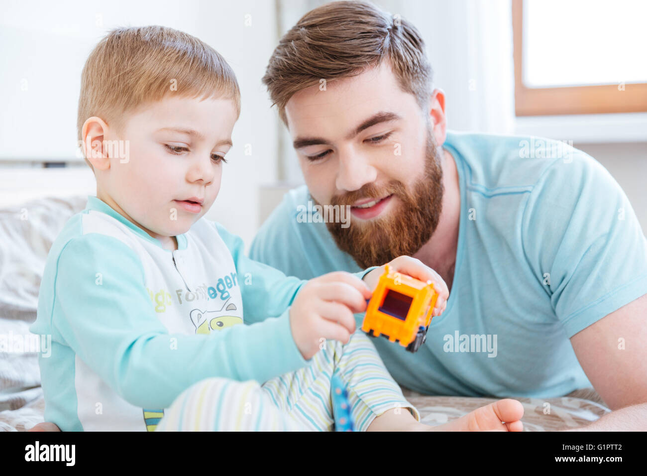 Dad and son playing with toys on bed at home Stock Photo - Alamy