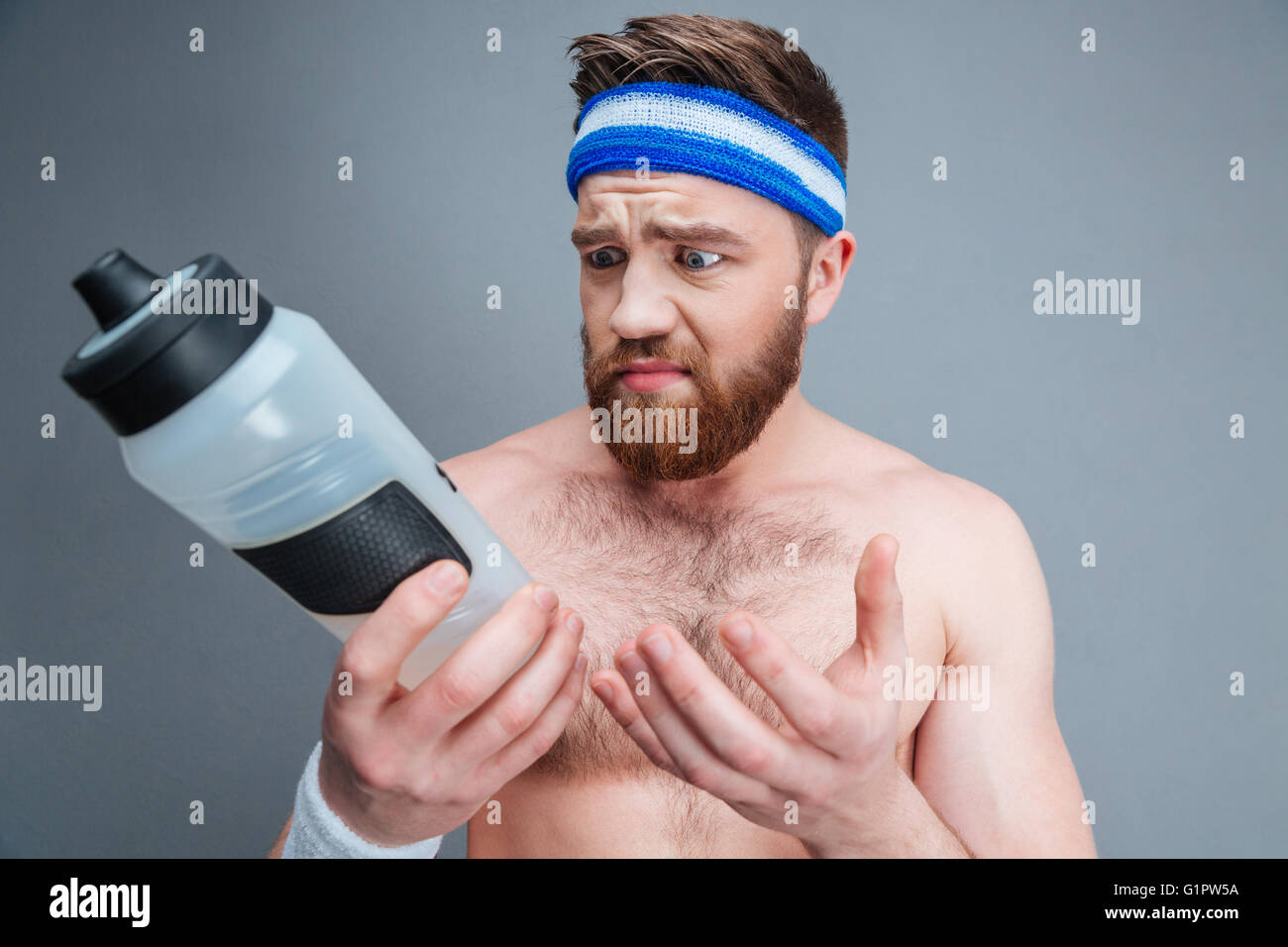 Portrait of sad upset young sportsman with empty bottle for water over ...
