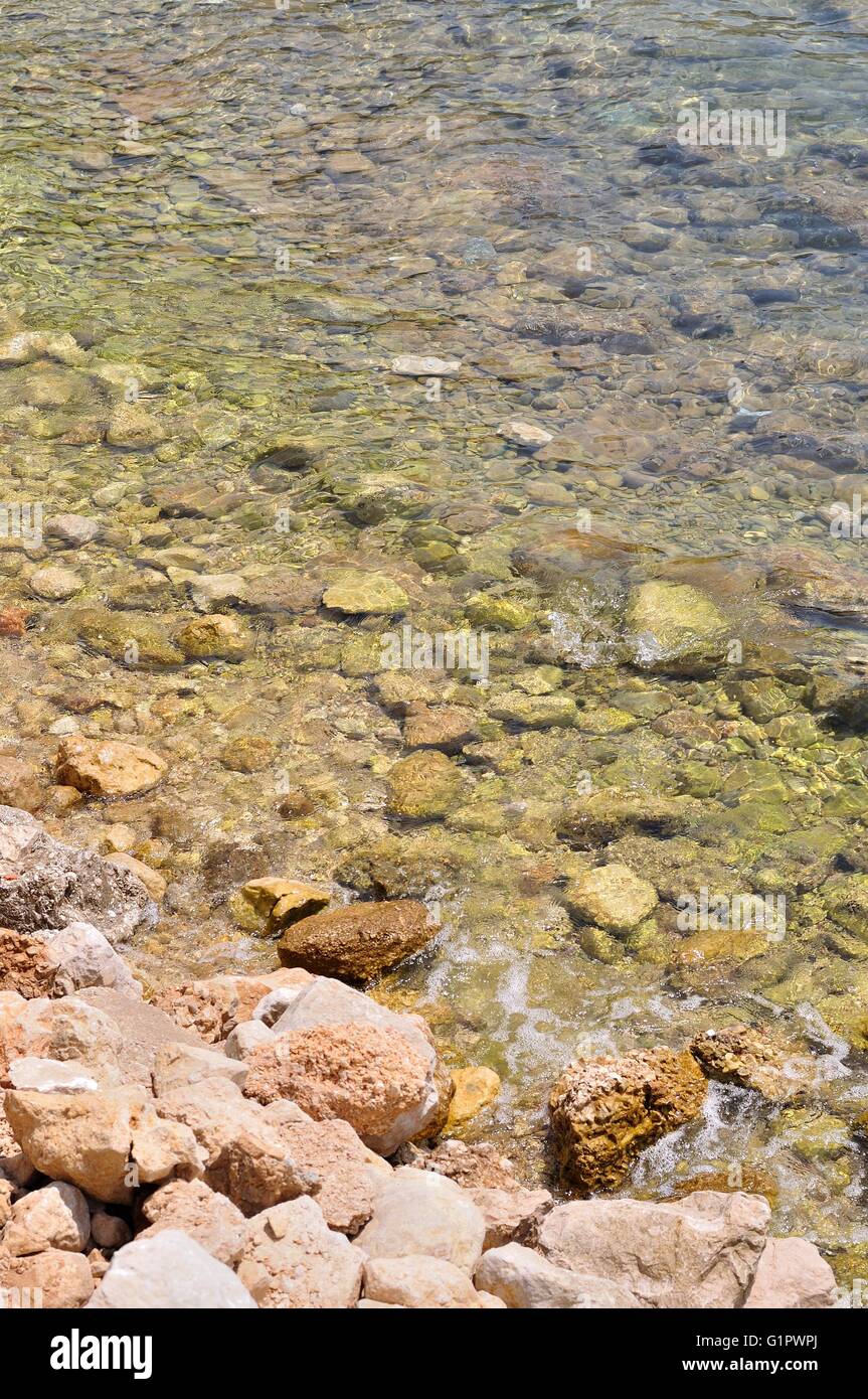 Beach with stones and crystal clear water. Vertical photo Stock Photo ...