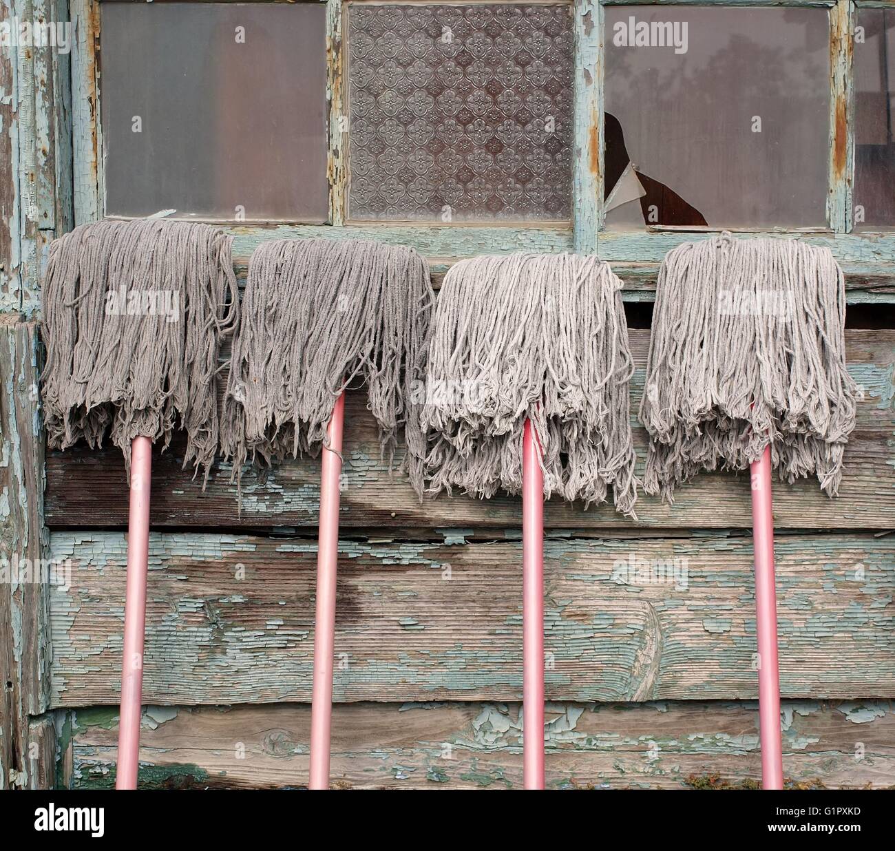 Four Chinese style mops are leaning against an old house so they can ...