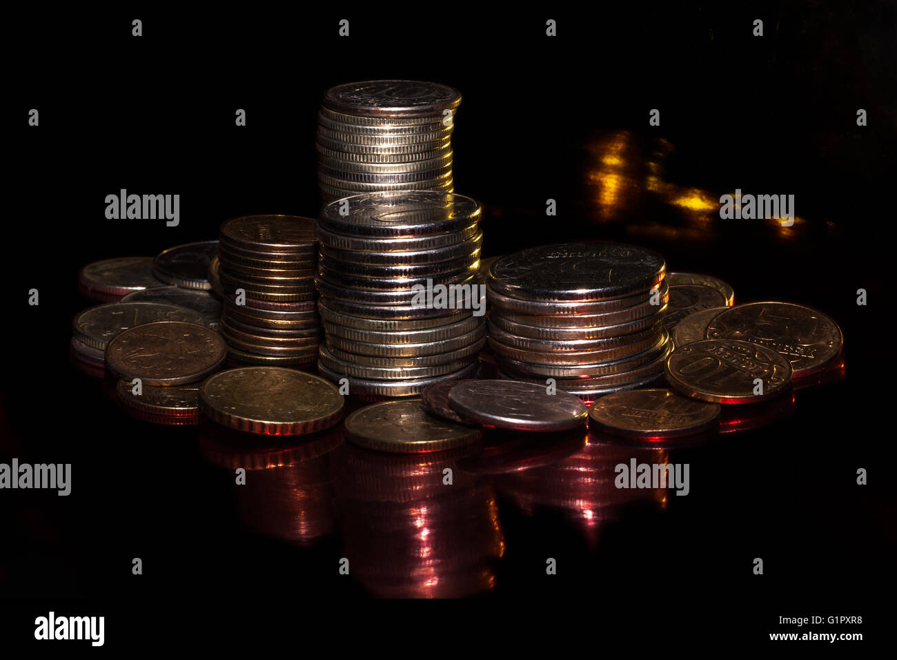 small coins against a dark background with shadows and color patches of ...