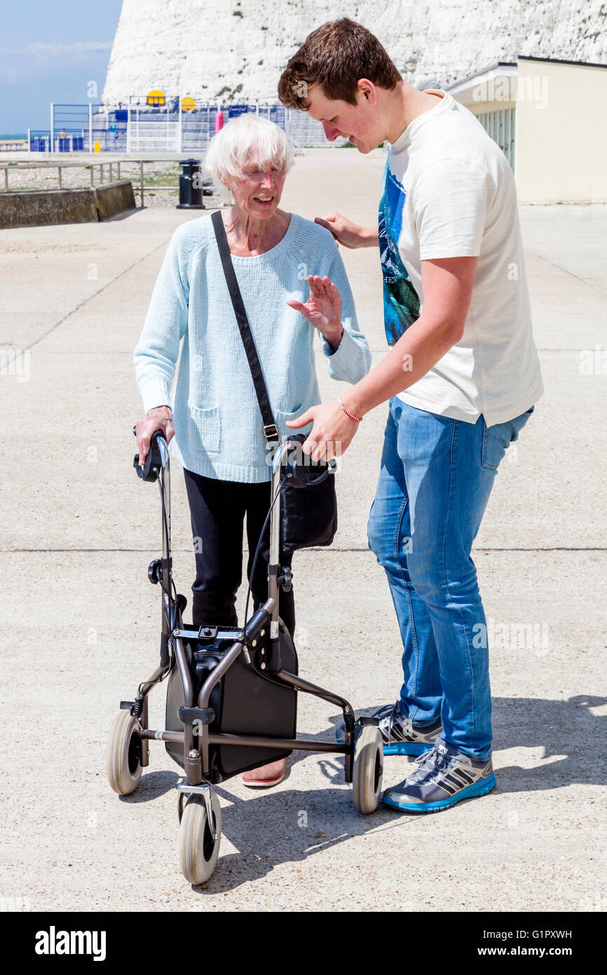 An Elderly Disabled Woman Using A Rollator Walking Aid Helped By Her ...