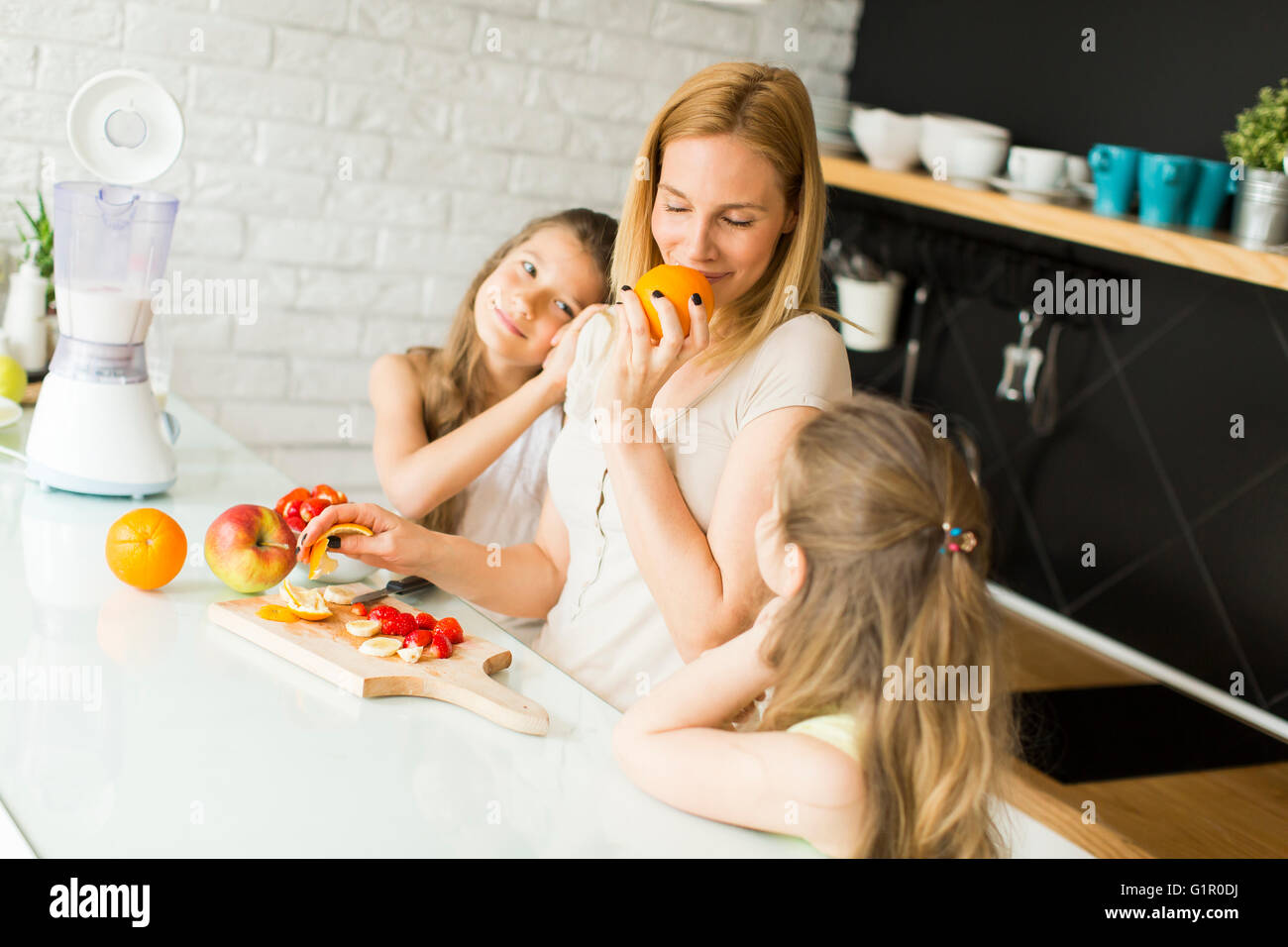 Woman and two girls preparing fruits for smoothie Stock Photo - Alamy