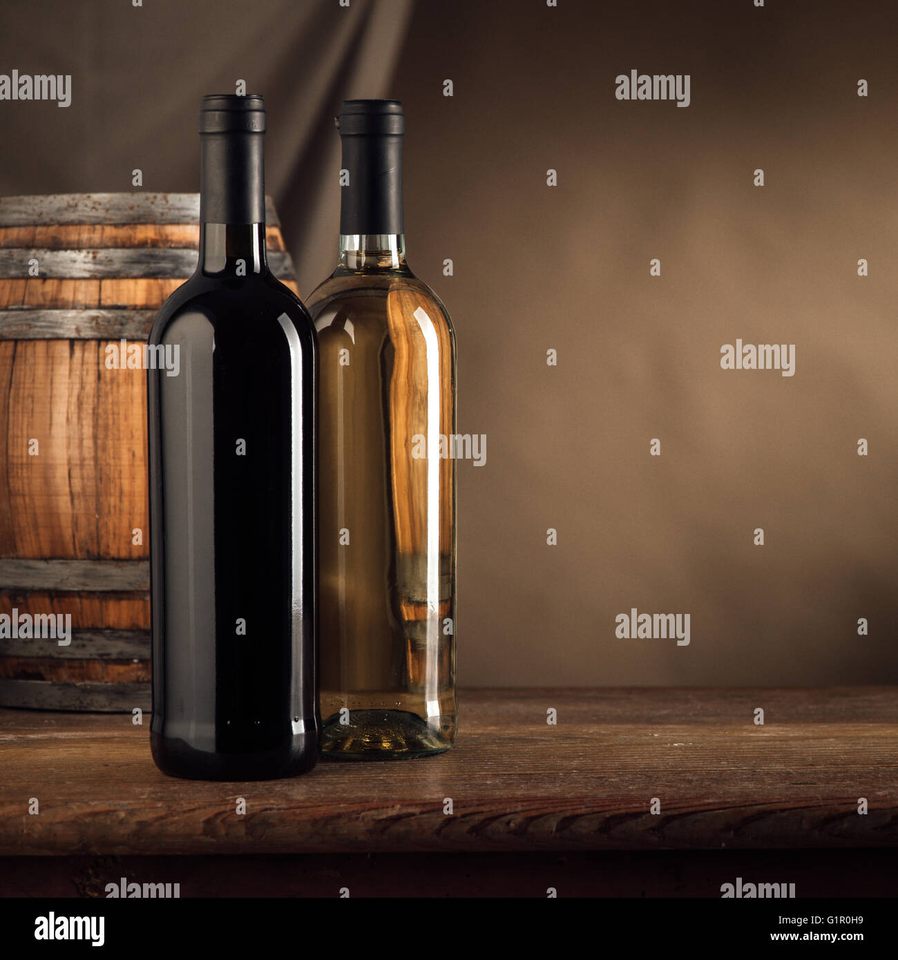 Red and white wine bottles and wooden barrel on the cellar table, wine ...