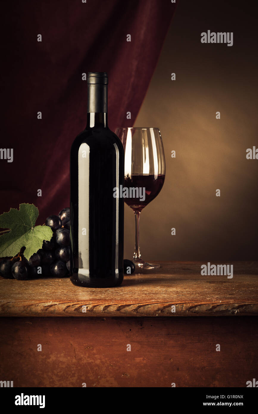 Red wine bottle and glass on a rustic wooden table, red cloth on ...