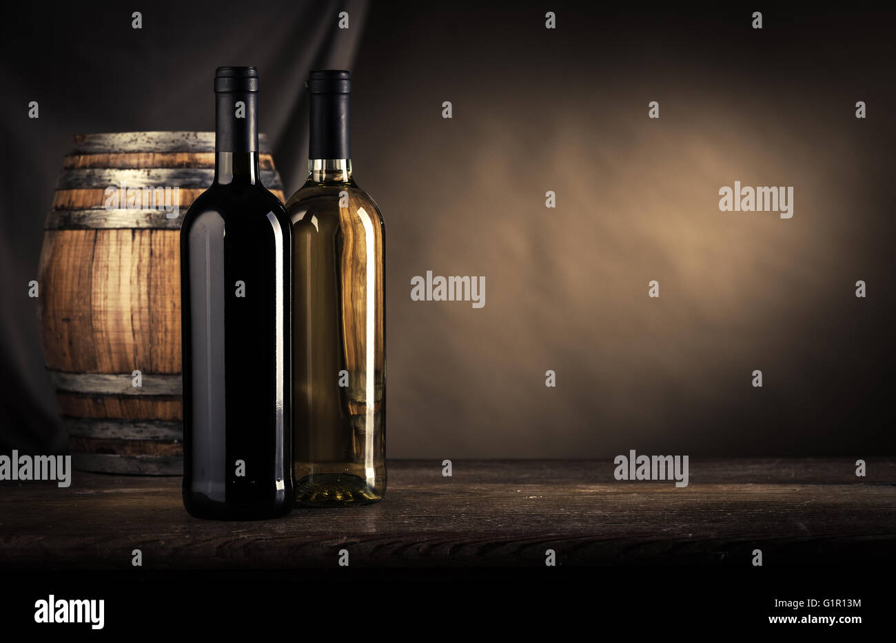 Red and white wine bottles and wooden barrel on the cellar table, wine ...