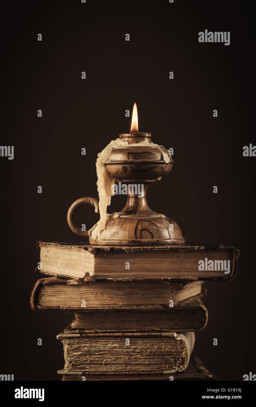 Pile of ancient books and lit candle on top hi-res stock photography ...