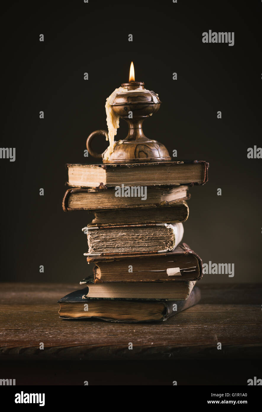 Pile of ancient books and lit candle on top hi-res stock photography ...