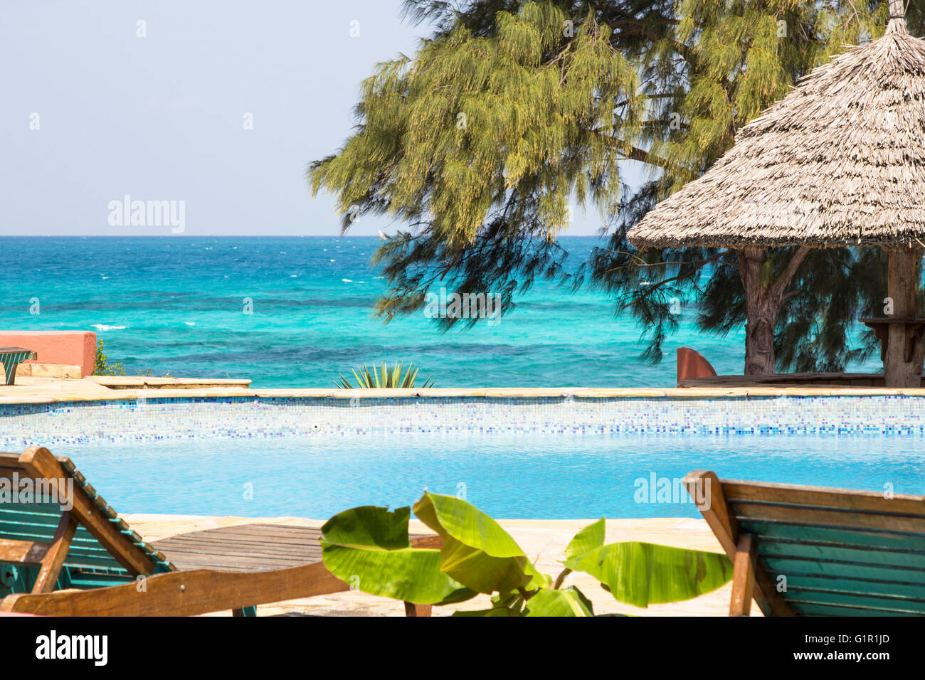 Summer holiday swimming pool resort with deckchairs against of blue ...