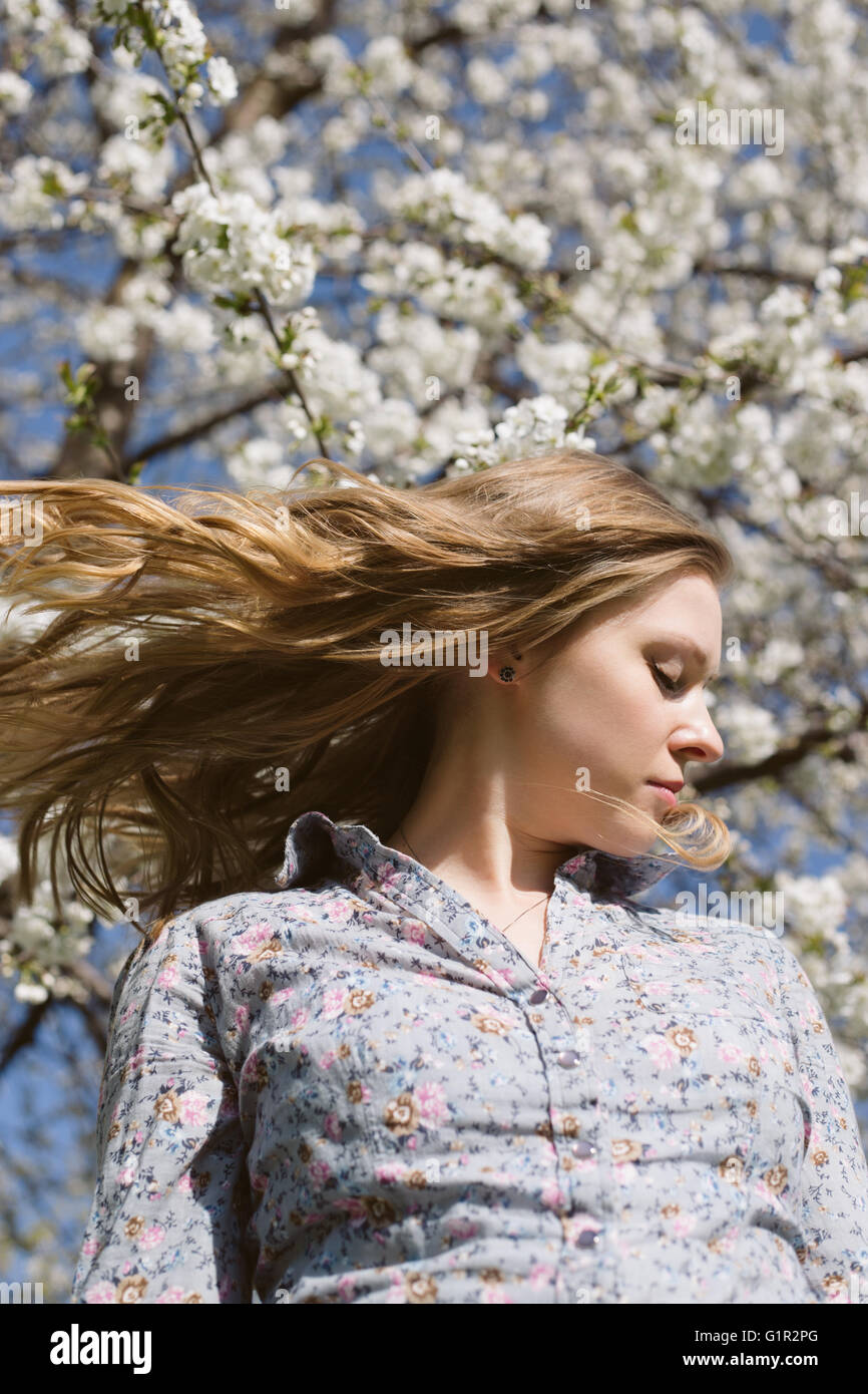 Portrait of a young woman standing in front of a spring blossom tree ...