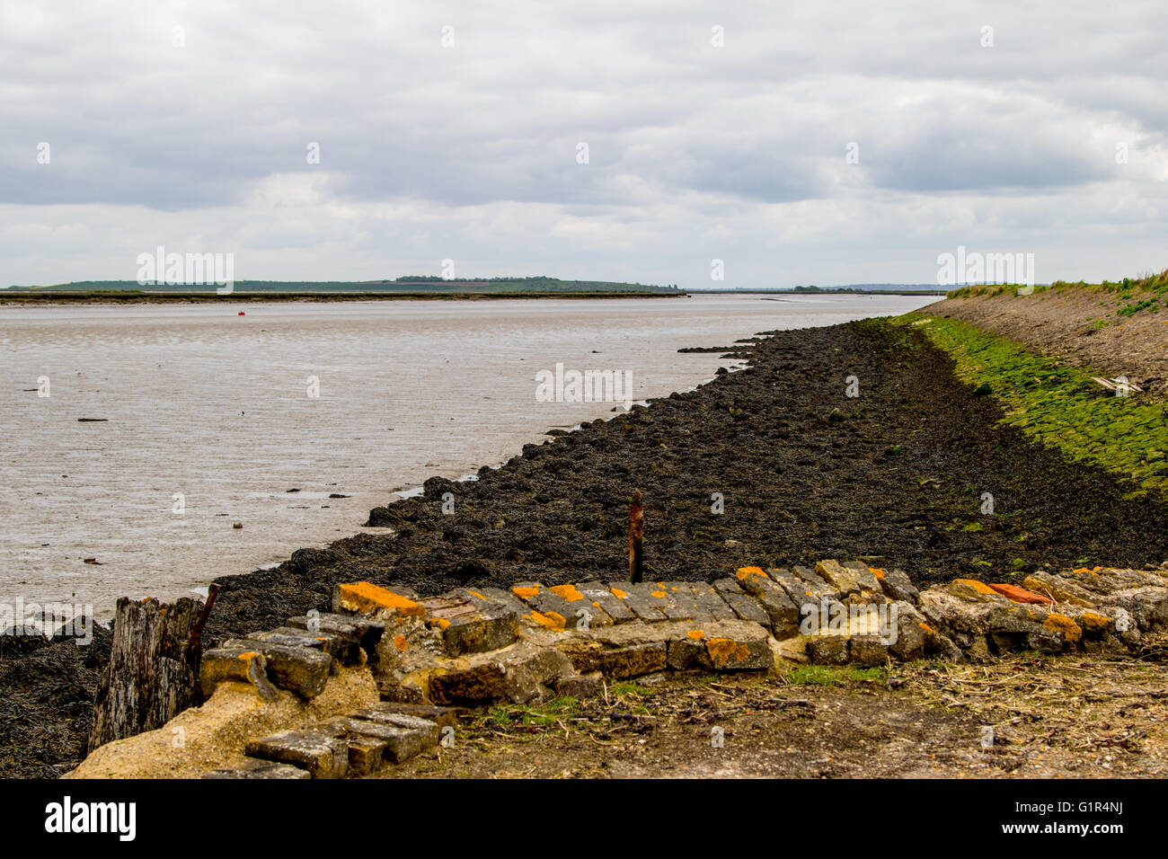 Banks of the River Swale at low water, brick wall in the foreground ...
