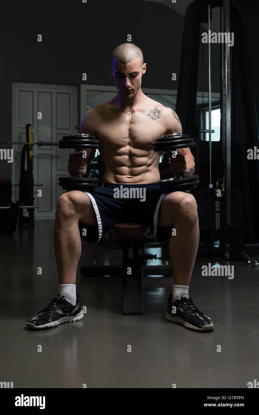 Portrait Of A Physically Fit Young Man In A Healthy Club With Dumbbells ...