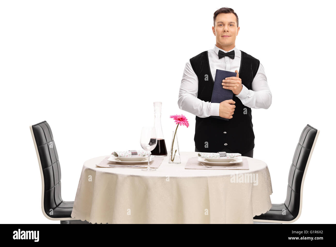 Young waiter standing next to a restaurant table and holding a menu ...