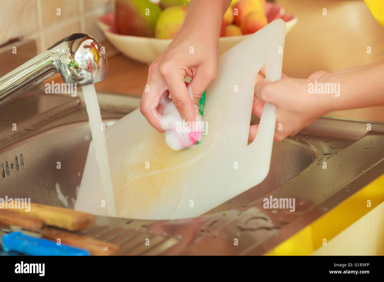 Household. Closeup woman doing the washing up in kitchen cleaning ...