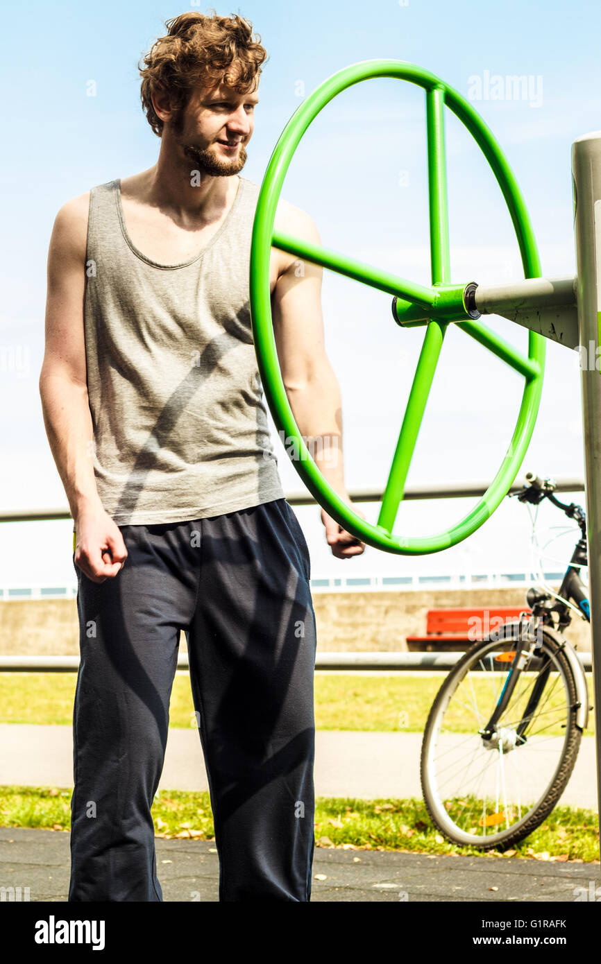 Muscular active man in training suit exercising working out at outdoor ...