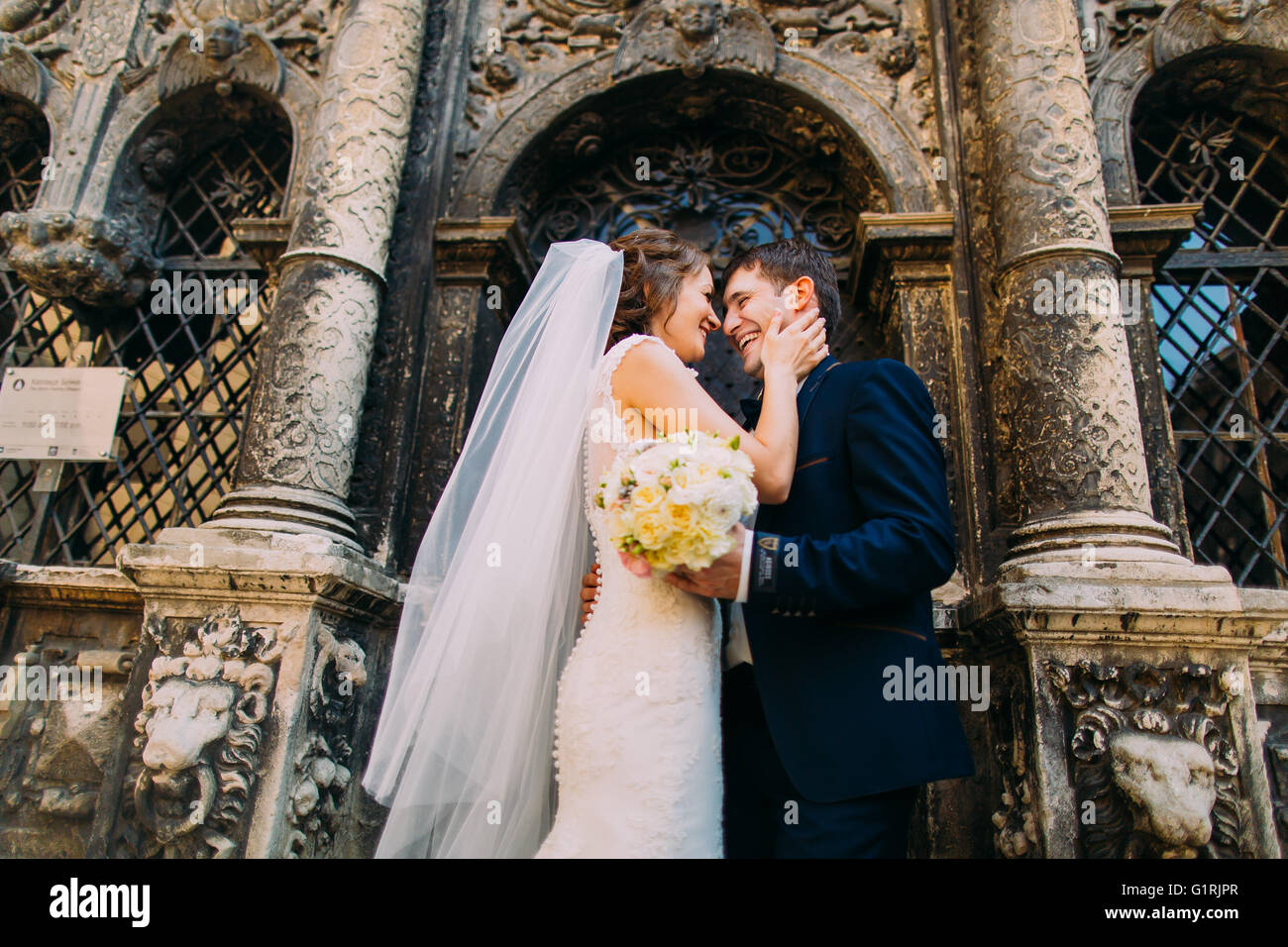 Romantic newlywed bride and groom laughing in front of old bulding with ...