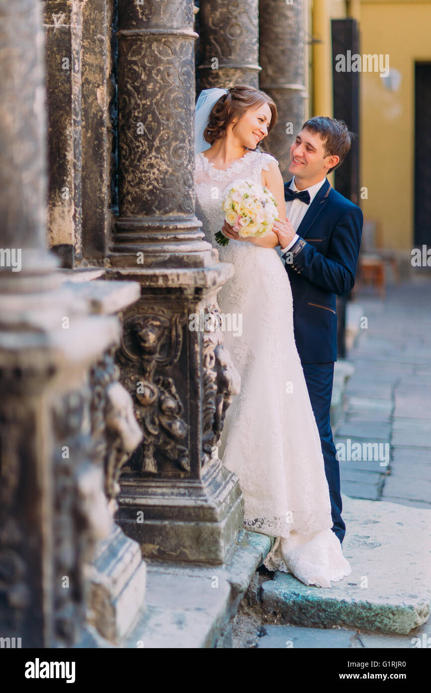 Sensual romantic groom hugging beautiful bride from behind with bouquet ...