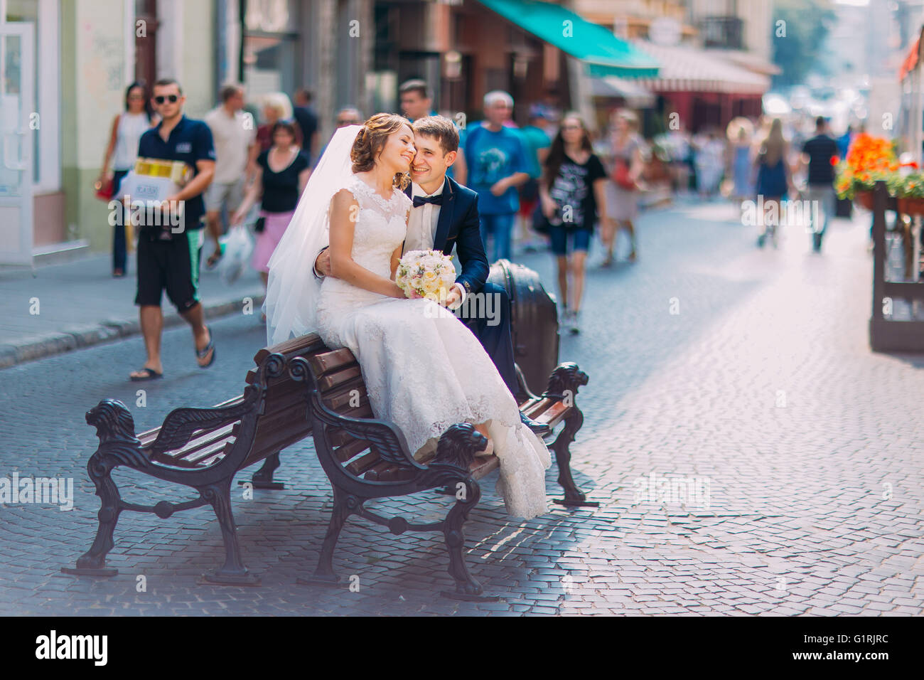 Beautiful bride and groom sitting on the bench having fun Stock Photo ...