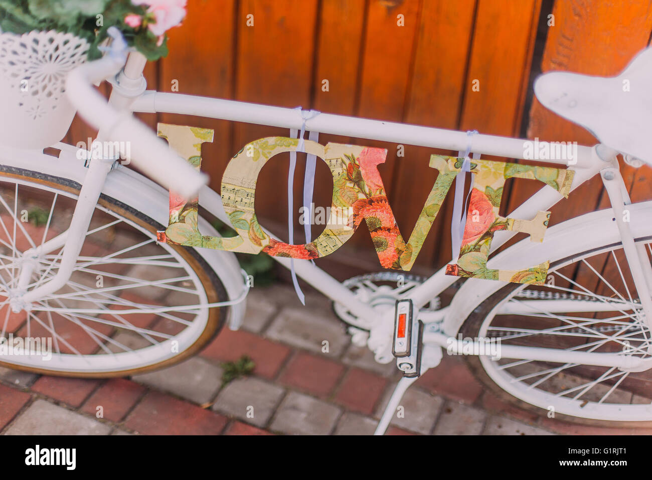 Decorative white bicycle with basket of flowers and word love, indoors ...