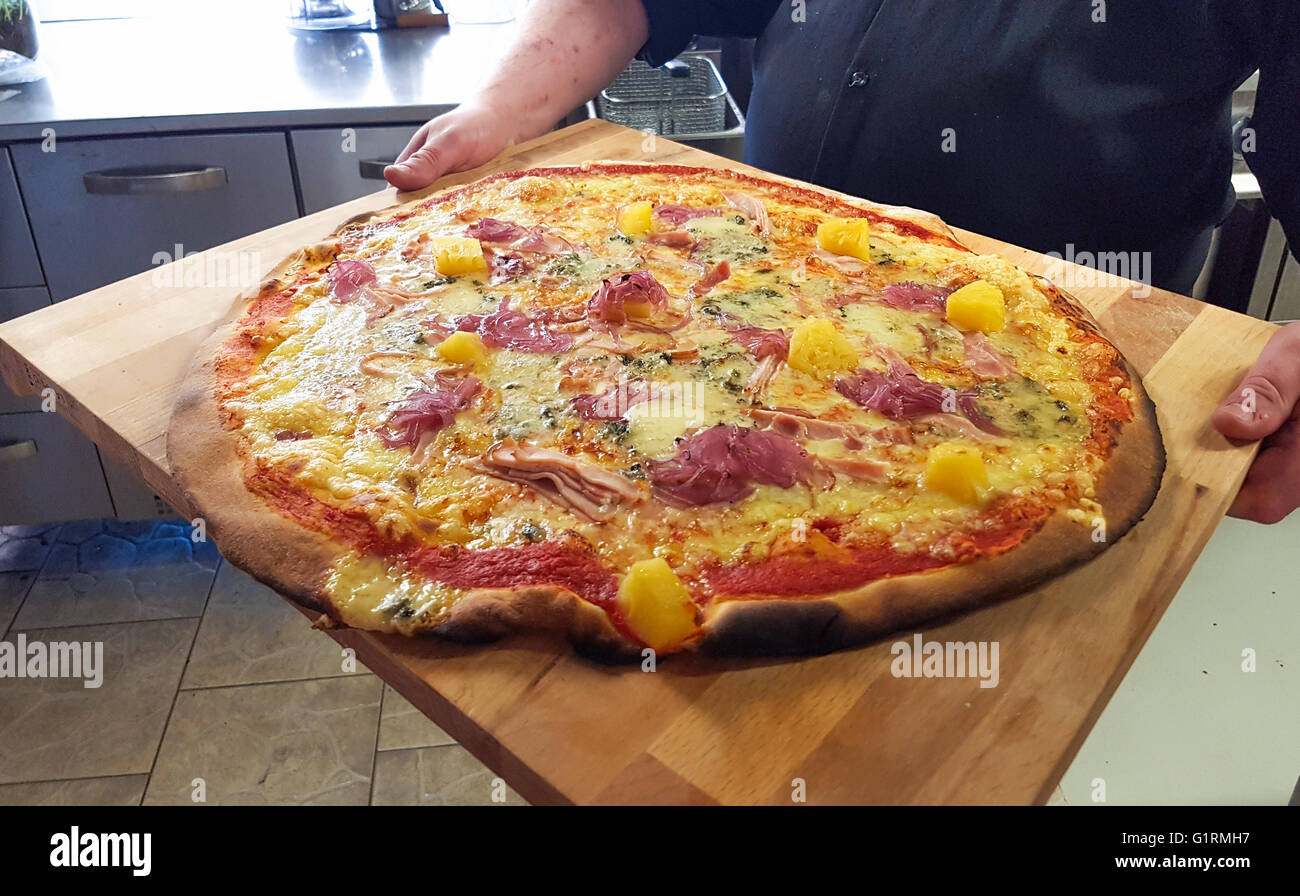 Large family size pizza, on a wooden cutting board, at a restaurant ...