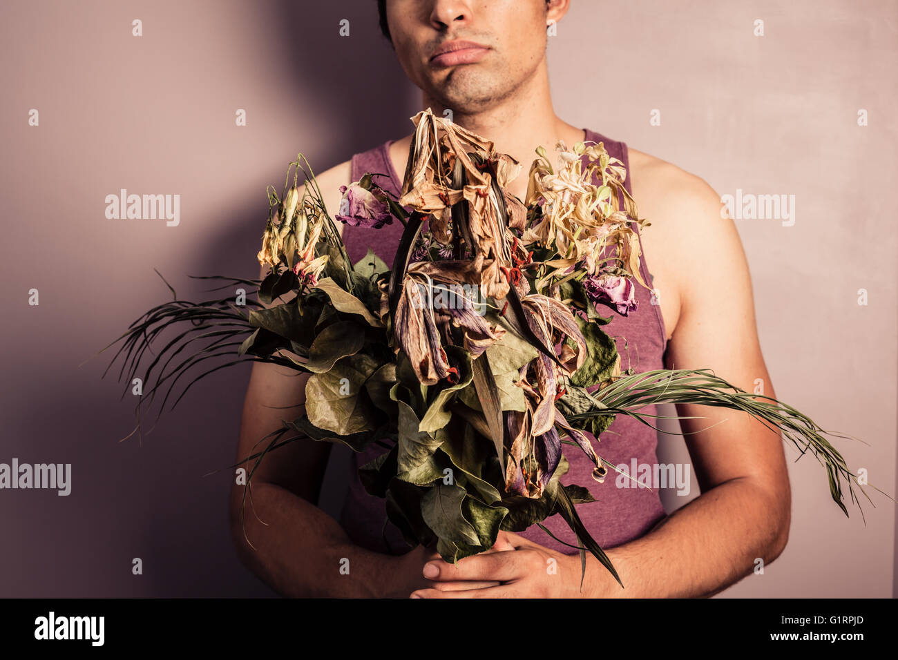 A sad young man is holding a bouquet of dead and withered flowers Stock ...