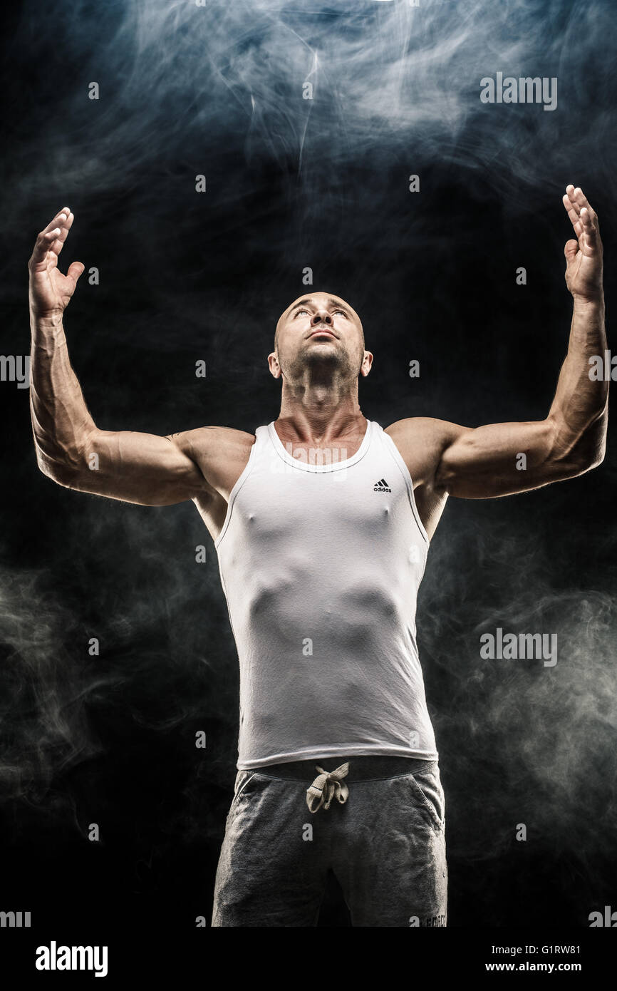 Muscular sportsman with arms raised looking up Stock Photo - Alamy