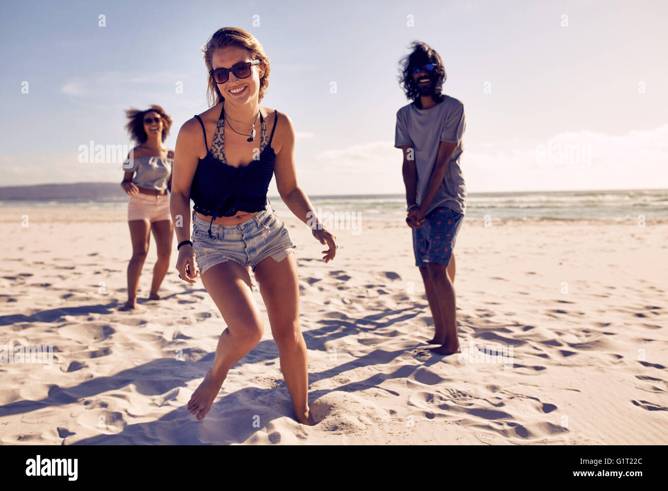 Portrait of beautiful young woman enjoying on the beach with friends in ...