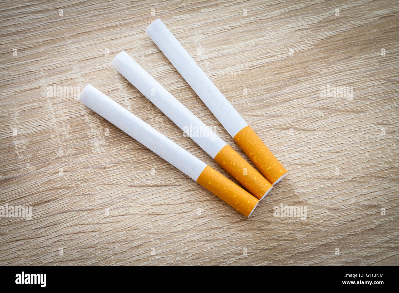 three cigarettes on a woody background Stock Photo - Alamy