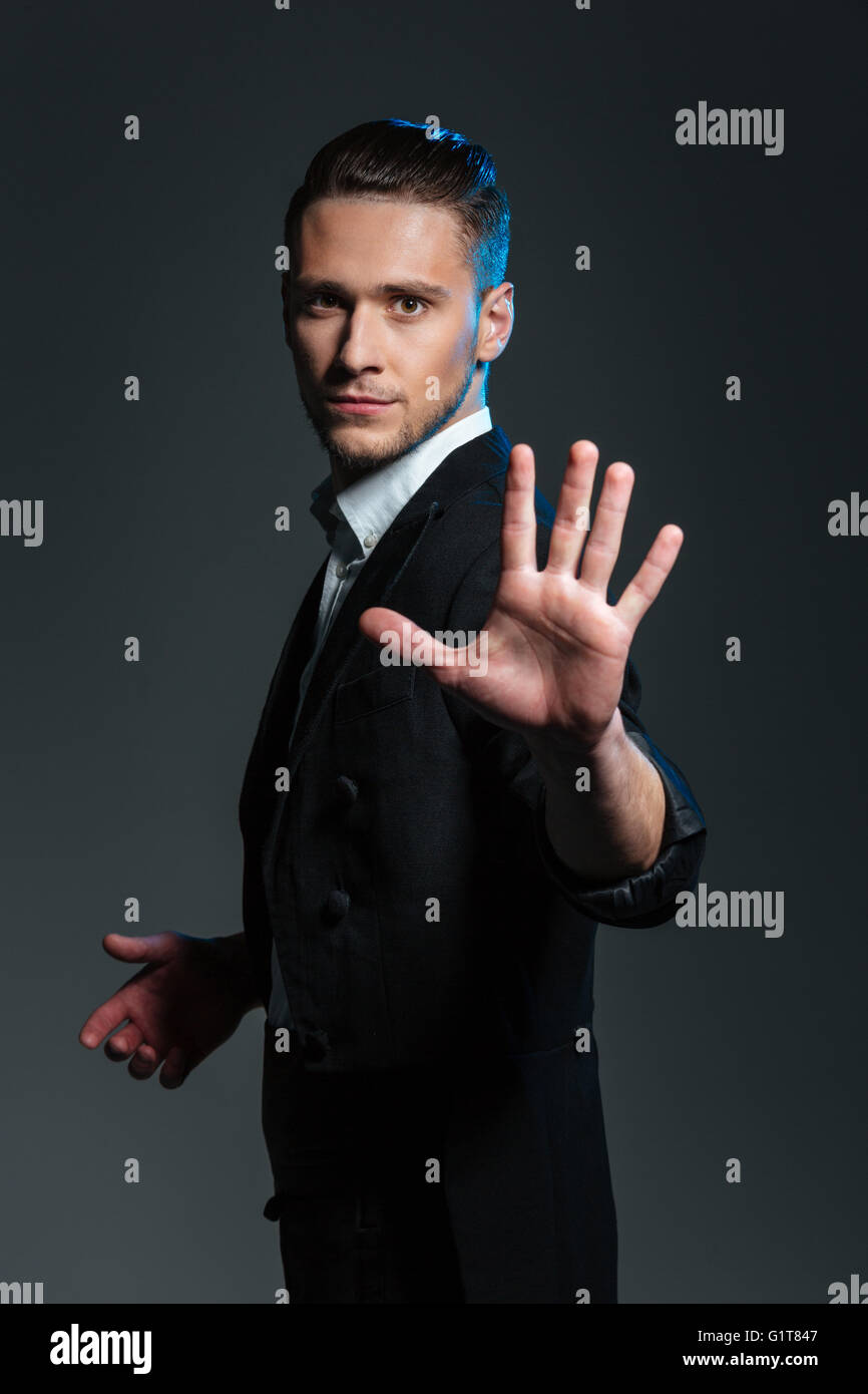 Handsome young man magician showing his palm over grey background Stock ...