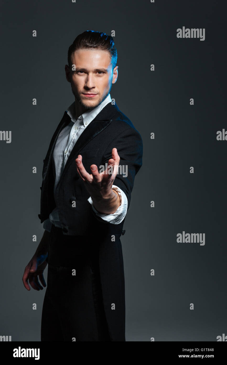 Attractive mysterious young magician holding something on palm over ...