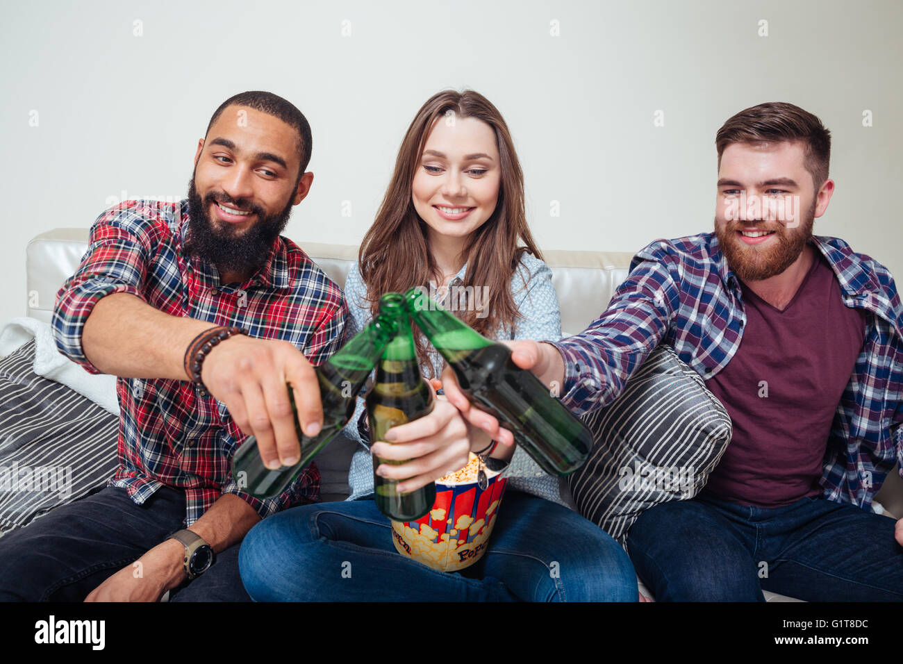 Cheerful young friends drinking beer at home together Stock Photo - Alamy