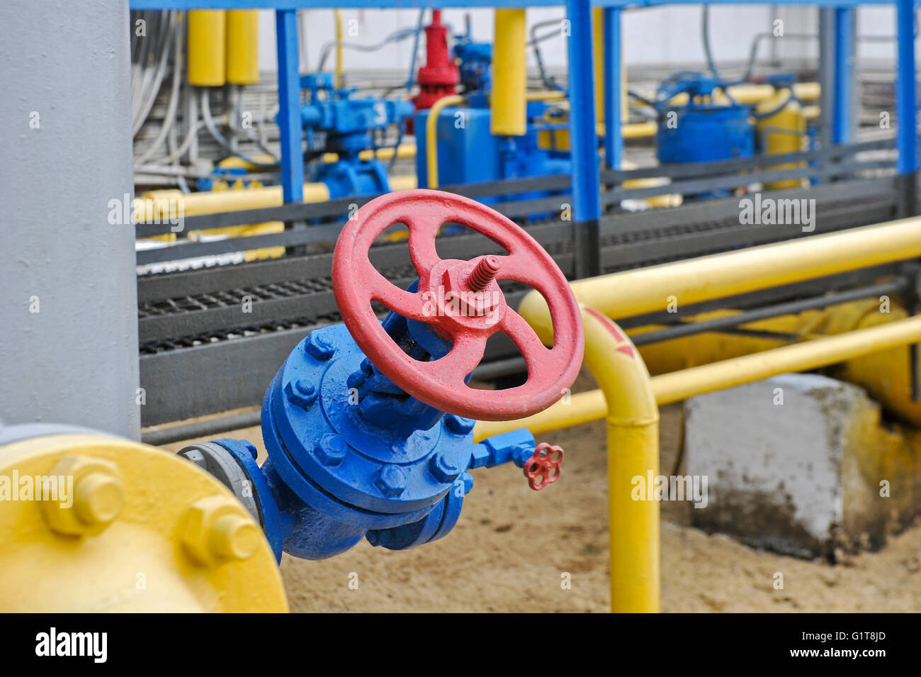 Red faucet with steel pipe in natural gas compressor station in summer ...
