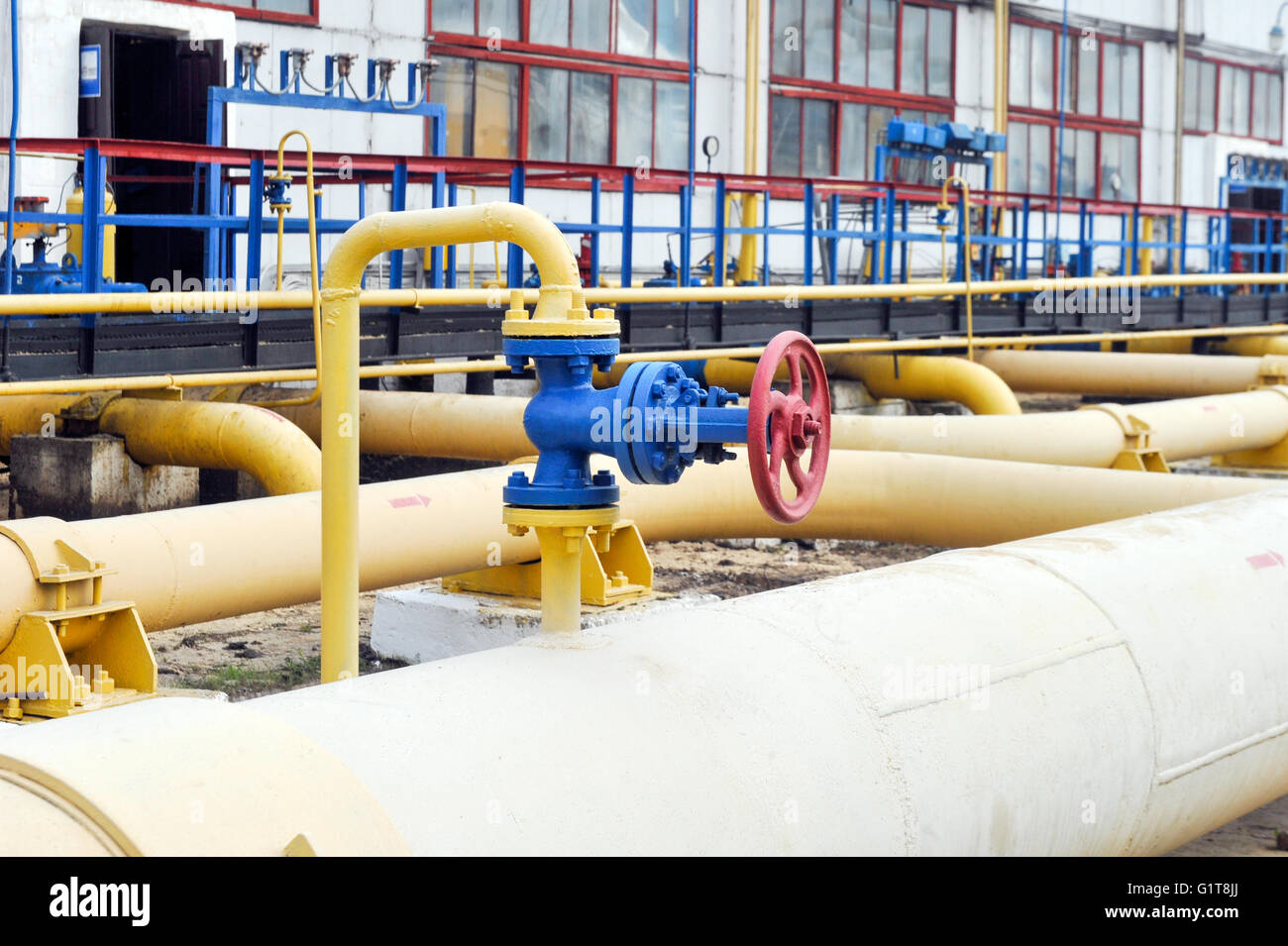 Red faucet with steel pipe in natural gas compressor station in summer ...