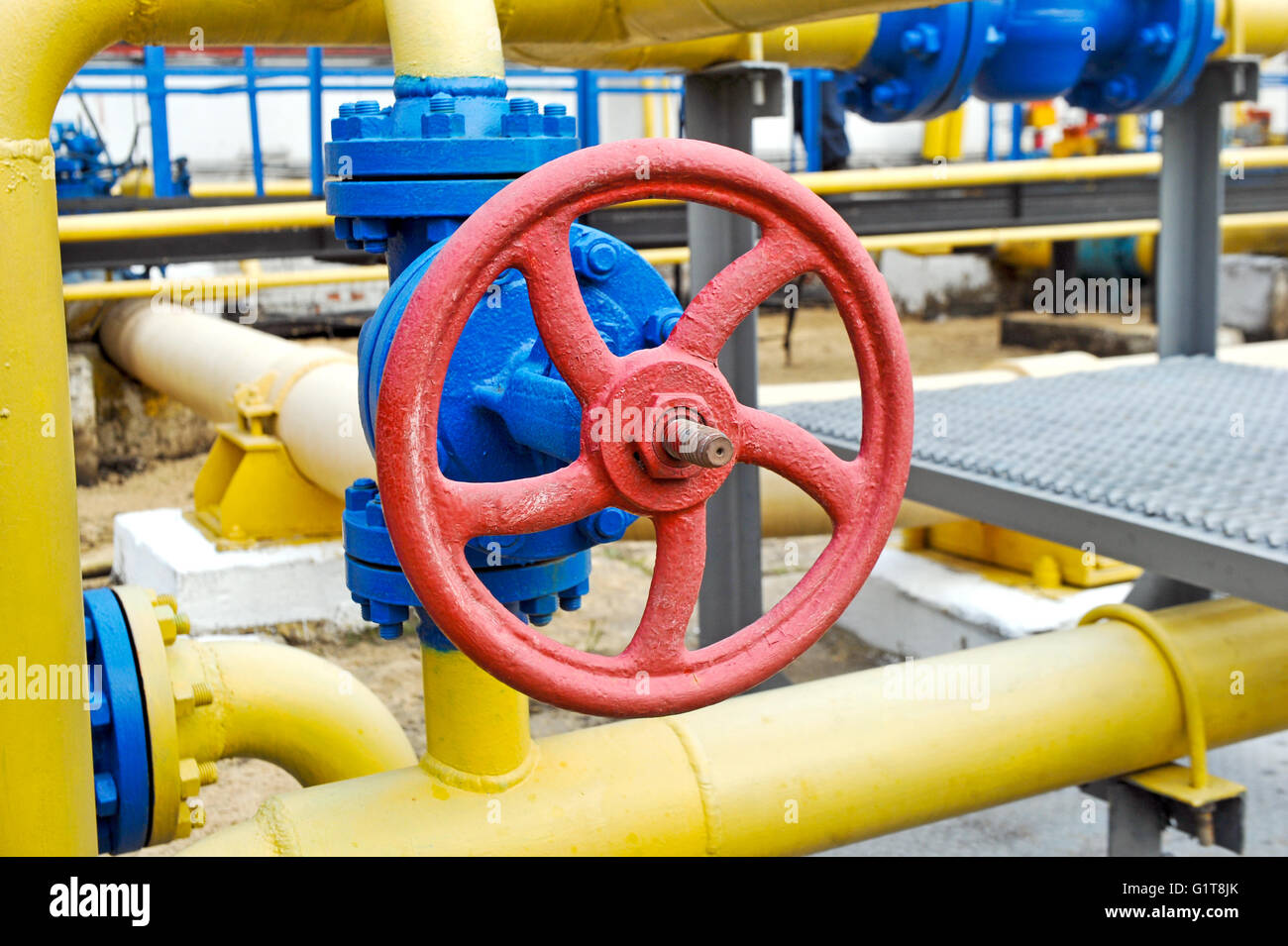 Red faucet with steel pipe in natural gas compressor station in summer ...