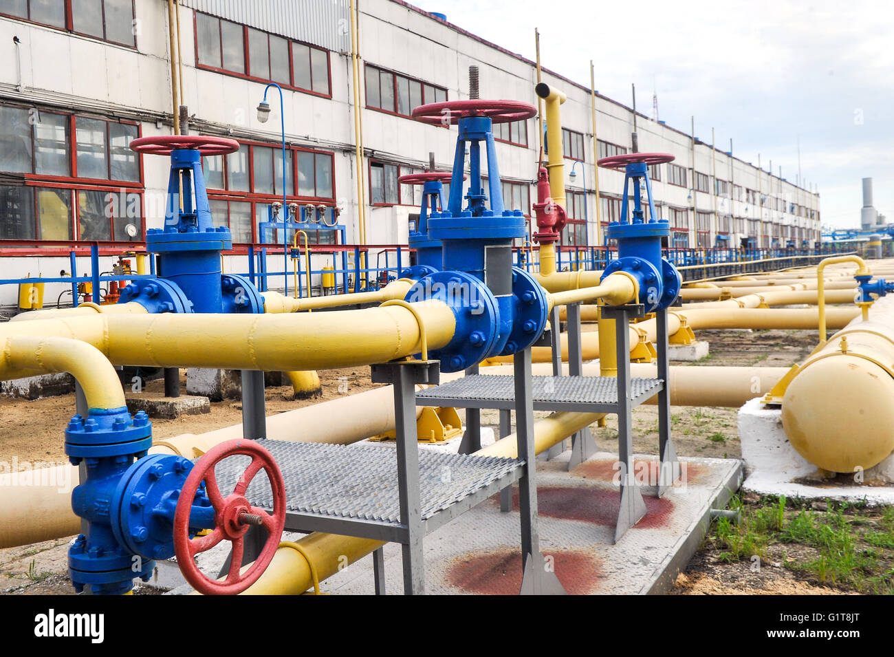 Red faucet with steel pipe in natural gas compressor station in summer ...