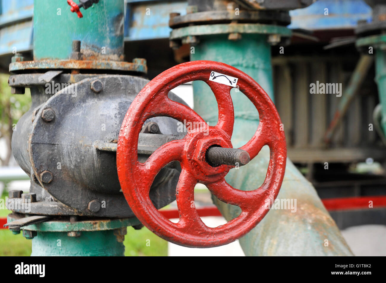 Red faucet with steel pipe in natural gas compressor station in summer ...