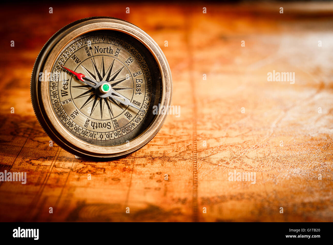 Vintage still life. Vintage compass lies on an ancient world map in ...