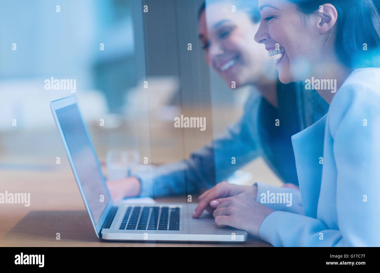 Laughing businesswomen working at laptop Stock Photo - Alamy