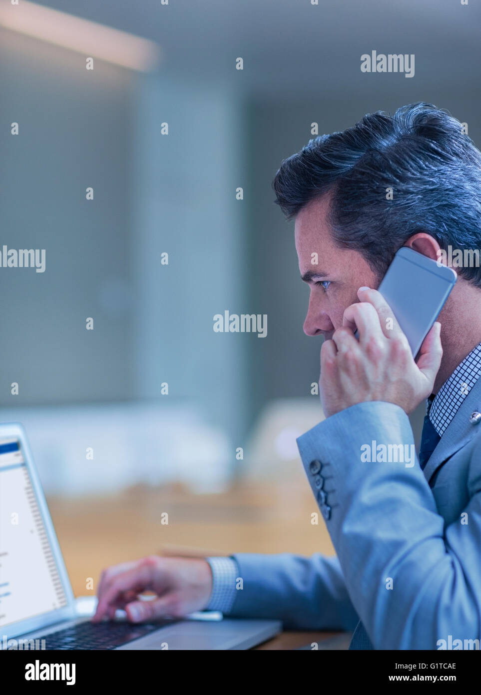 Businessman working on a laptop and talking on mobile phone Stock Photo ...