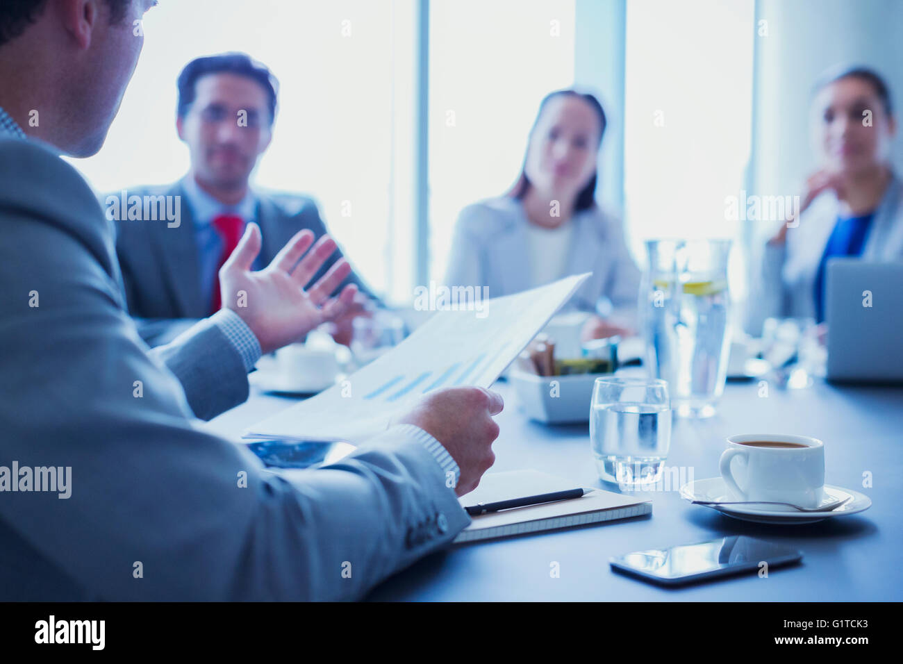 Businessman leading meeting explaining paperwork in conference room ...
