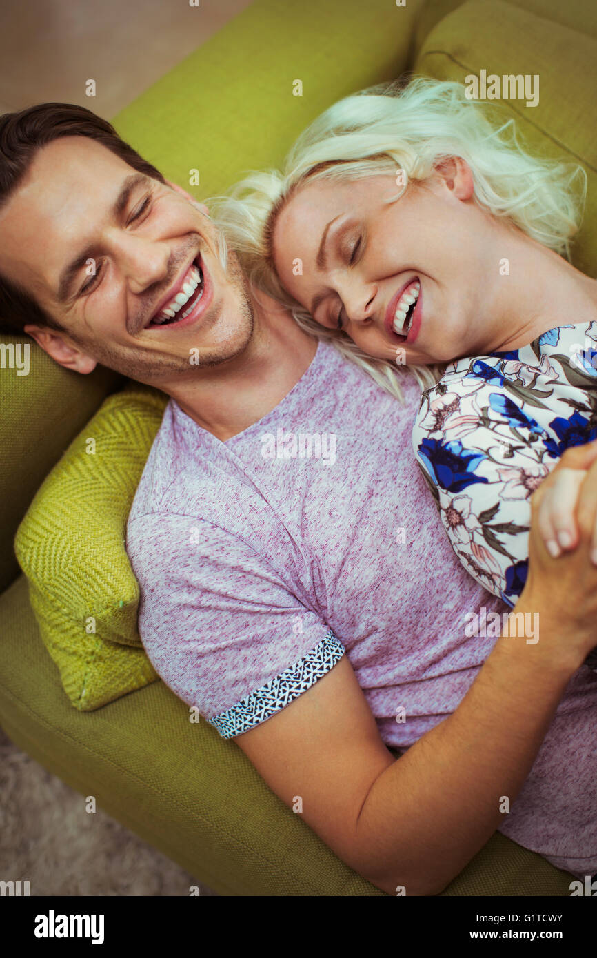 Affectionate laughing couple laying on sofa with eyes closed Stock ...