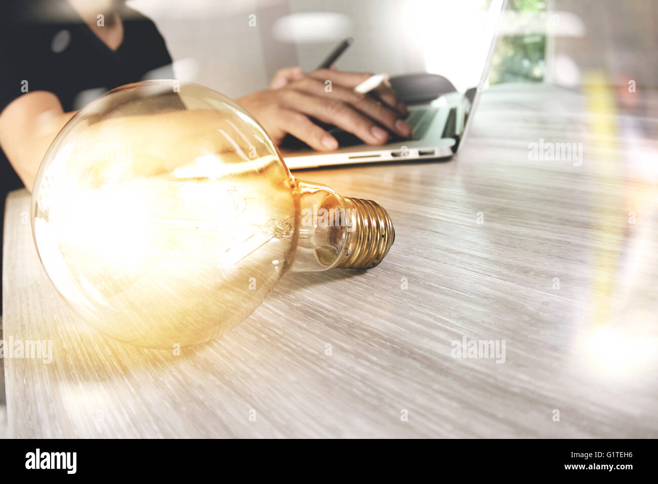 light bulb with designer hand working with laptop computer and creative ...