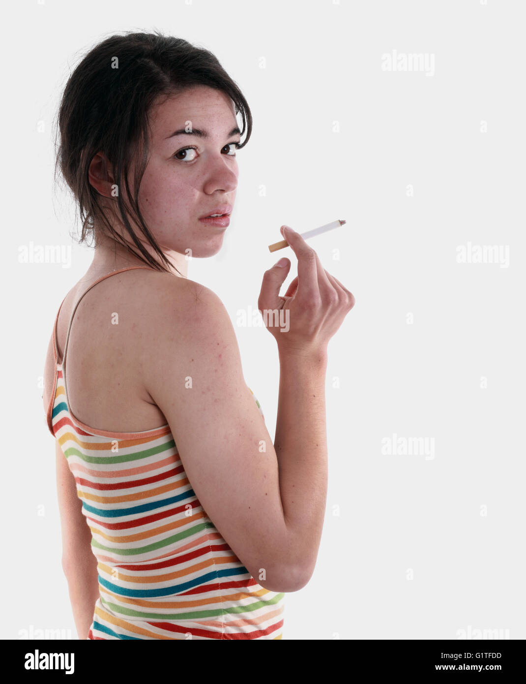 Furtive looking young mixed race woman with a cigarette, underage and ...